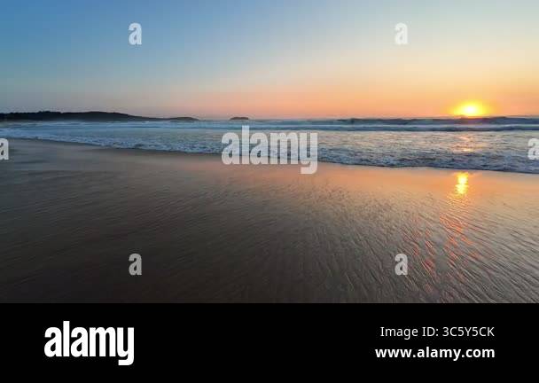 A peaceful and tranquil beach scene at sunset, showcasing gentle waves ...