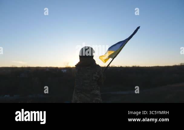Female ukrainian army soldier lifting national banner in hill. Young ...
