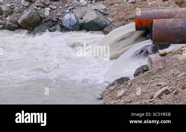 mountain river water flowing through temporary pipe bridge across the ...