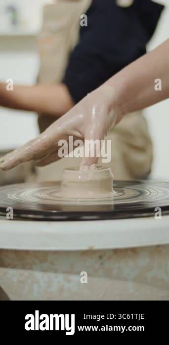 Hands of a pottery instructor guiding a student on a pottery wheel ...