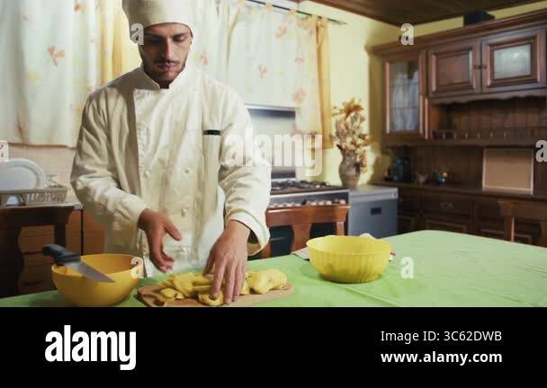 Italian Man Chef In Uniform Peels Potatoes On Wooden Cutting Board At ...