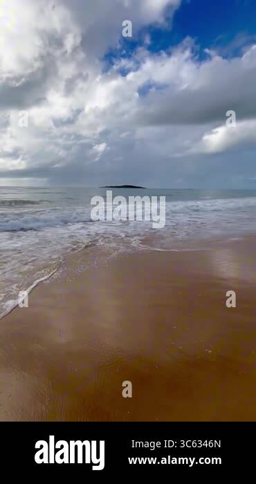 Quiet coastal scene capturing soft waves of the ocean hitting a sandy ...