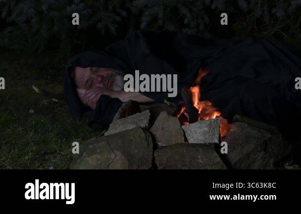 A black-clad traveller took a campfire break in the wilderness Stock ...