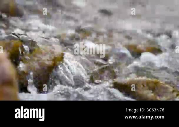 Water gurgles over stones in mountain creek close up, detail from ...
