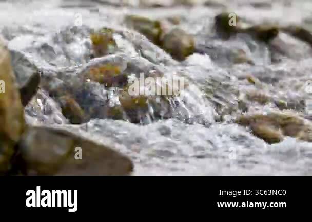 Water gurgles over stones in mountain creek close up, detail from ...