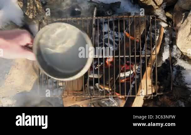 Top view of male hand puts boiler with water over bonfire at winter ...