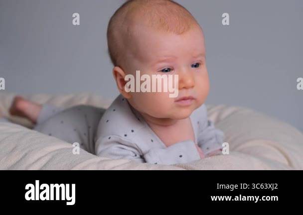 Portrait of a curious newborn baby lies in a cradle at home in the ...