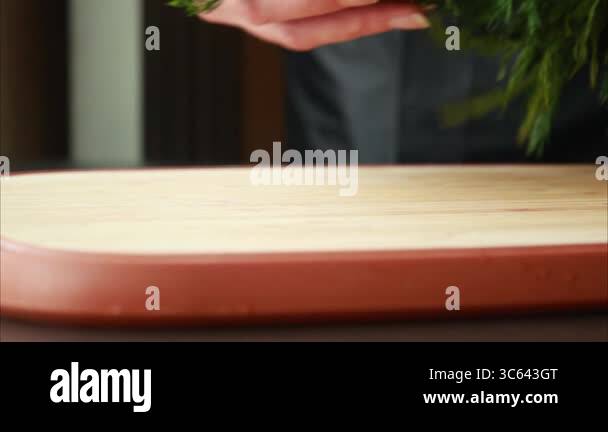 woman hands chopping fresh dill on a wooden cutting board close-up ...