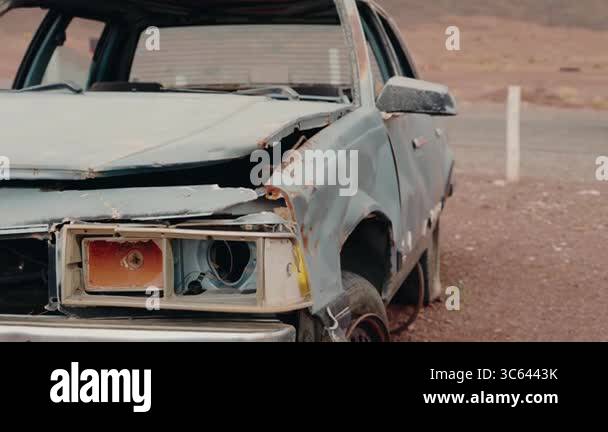 A wrecked, rusty, and dusty old car sits abandoned in the desert in ...