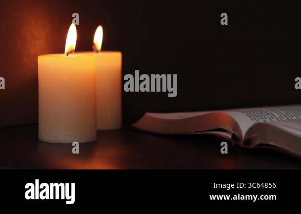 Studying holy bible in darkness with candles burning with bright flame ...