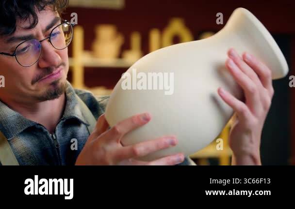 Caucasian man potter in craft shop looking examine vase clay handmade ...