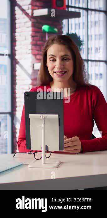 Vertical Video Focused woman smiling and waving during a web conference ...