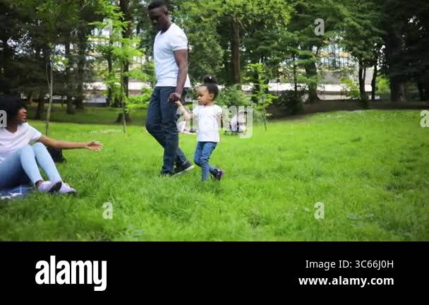 Beautiful happy African woman sitting on picnic blanket. Husband and ...
