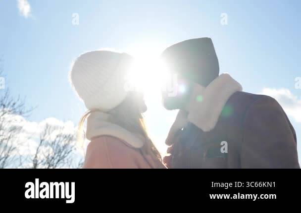 A couple enjoys a warm connection while facing the sunlight in winter ...