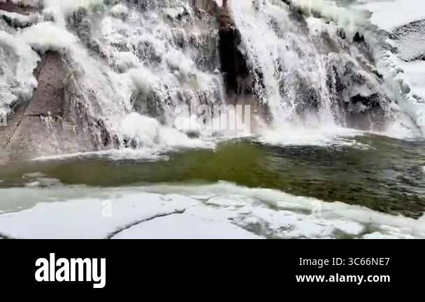 A stunning, frozen waterfall, beautifully encased in snow, showcases ...