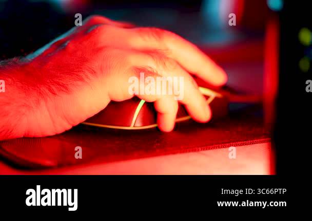 Close-up view of a hand using a gaming mouse in a dimly lit gaming ...