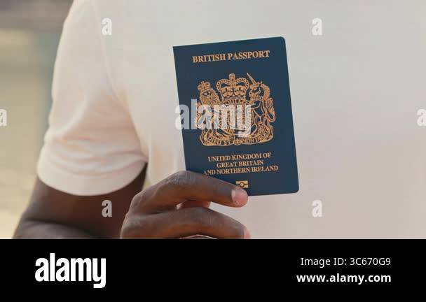 African American man in casual outfit holds British passport in hand ...