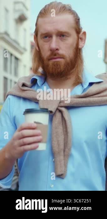 A stylish, fashionable man holding a steaming coffee cup stands ...