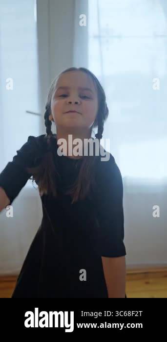 Young girl wearing Wednesday Addams costume style are dancing in a ...