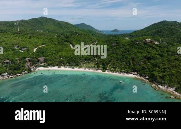 Emerald green water meets a tropical coastline with dense forested ...