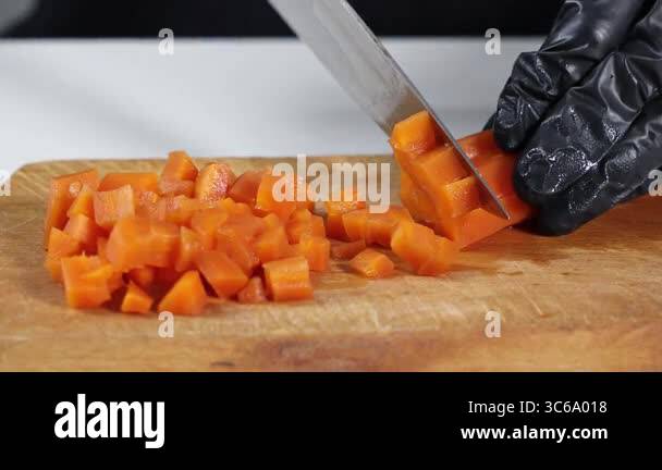 chef skillfully chops boiled carrot into perfect cubes on a wooden ...