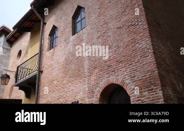 The brick wall of an old European-style building features windows, a ...