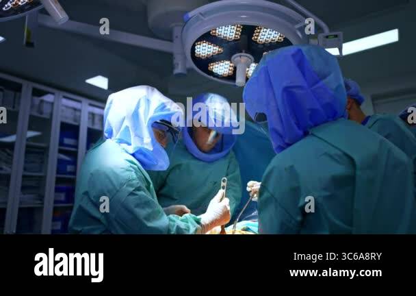 Male surgical team performs surgery under the round lamp. One of the ...