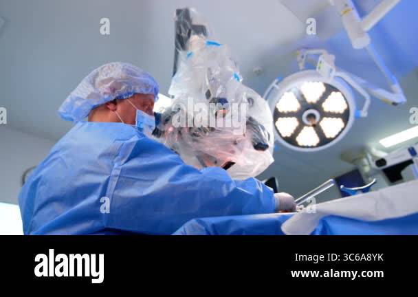 Professional male surgeon sits at the technological microscope. Low ...