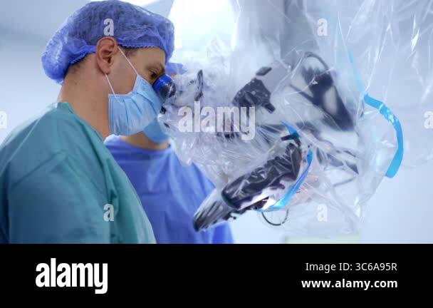 Surgeon looks intently at the binoculars of microscope. Doctor uses ...