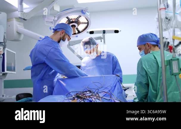Three uniformed medics work at the operating table. Multiple wires from ...