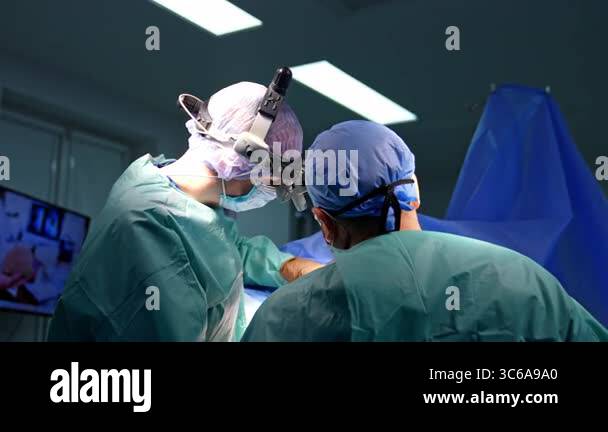 Rear view of the male broad-shouldered surgeon working at operation ...