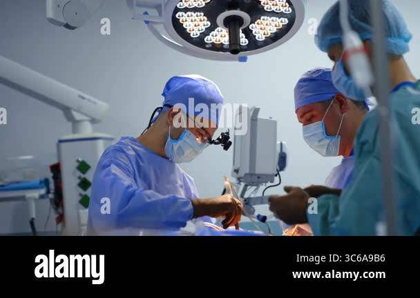 Surgeons do complex surgery. Surgeons work with precision in a well-lit ...