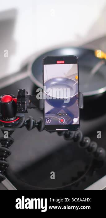 A smartphone is securely mounted on a tripod, aimed at a frying pan on ...