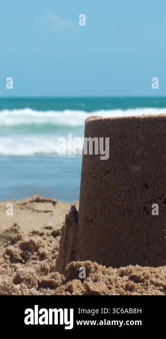 Sandcastle on a beach with ocean waves gently crashing in the ...
