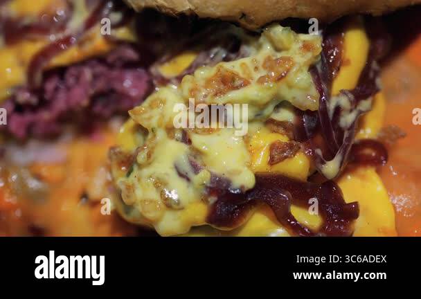 Close up of a loaded burger with melted cheese, caramelised onions, and ...