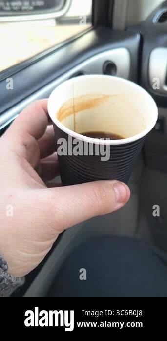 coffee in the driver's hands. a man holds a cup of coffee in a car ...