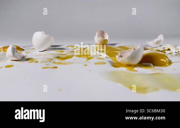 Messy broken eggs and shells on a white seamless background creates an ...