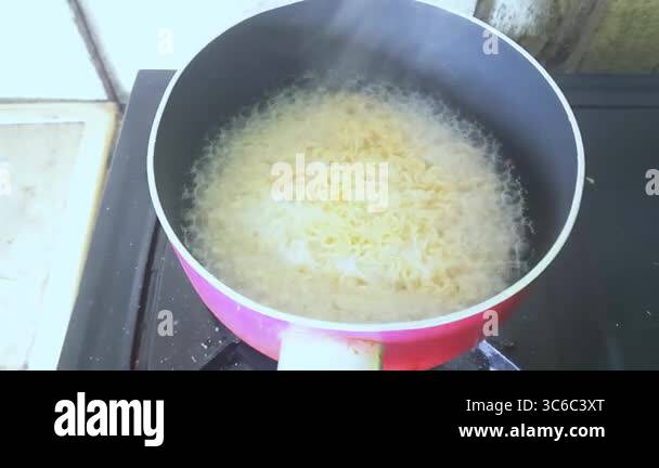 Noodles that are being boiled in hot water using a stove, the process ...