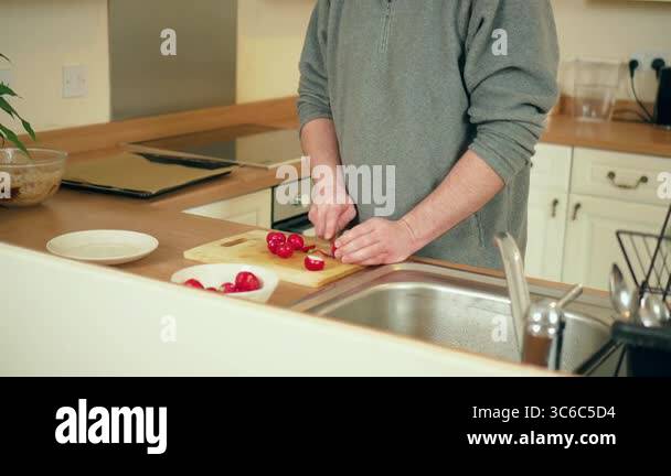 Man slicing fresh radishes on wooden cutting board in kitchen. Male ...