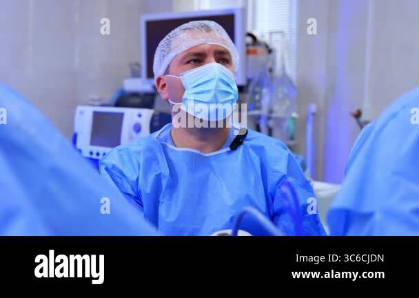 Male Caucasian surgeon looks up at the screen in front of him. Doctor ...