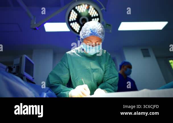 Female surgeon uses metal tool at operation. Low angle view at the ...