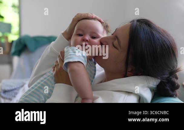 Mother holding baby close, gently caressing forehead, affectionate ...