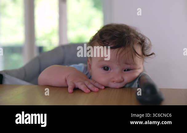 Baby chewing on table edge while sitting in high chair, teething ...