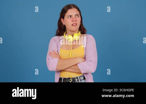 Concerned young Caucasian woman wearing yellow headphones and casual ...