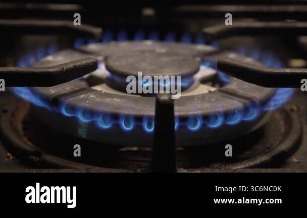 Gas stove flame. Close up of a gas stove burner igniting with a blue ...