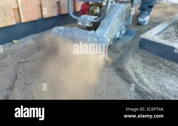 Worker consolidates the soil with a vibratory rammer. Soil compaction ...