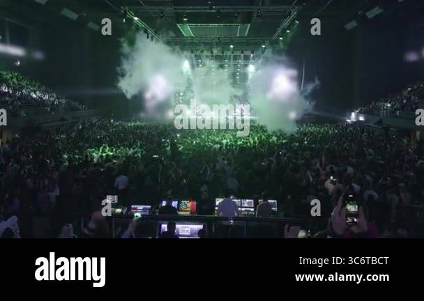 Phones glow in dark concert hall, wide view. People crowd filming ...