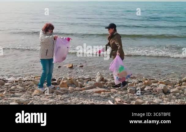 Two environmentalists clean up a polluted beach by picking up plastic ...