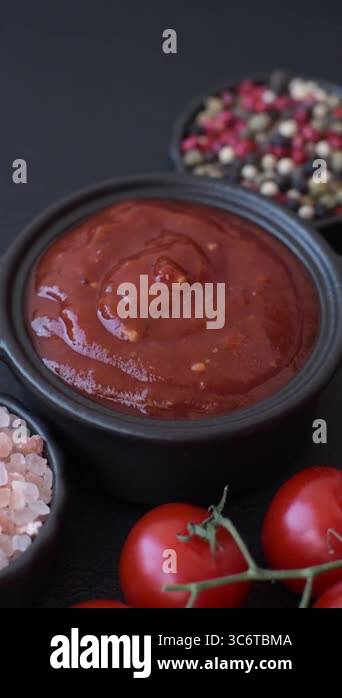 Red sauce or ketchup with salt and spices in ceramic sauce boat on dark ...