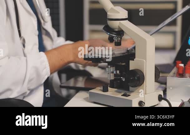 close - up of scientist holding microscope and examining blood in a ...